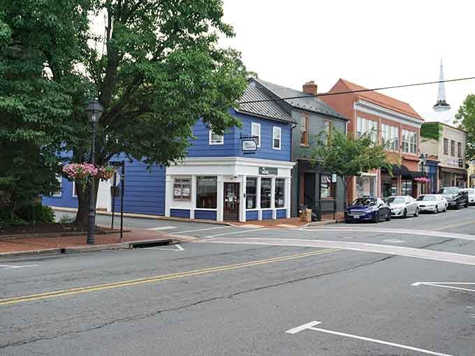 Charming local shops painted in deep blue and slate gray sit invitingly along a quiet, clean downtown street corner.