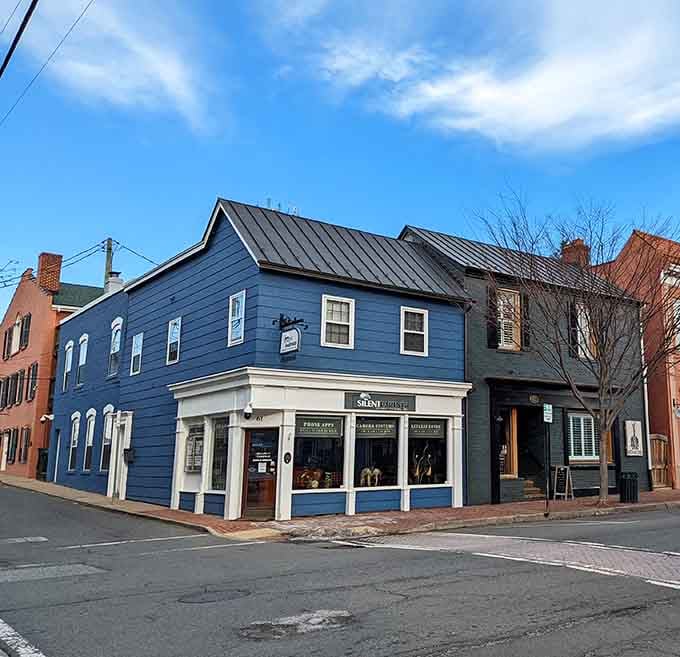 The striking blue facade of a historic corner shop stands out beautifully under a bright, cloud-dotted afternoon sky.