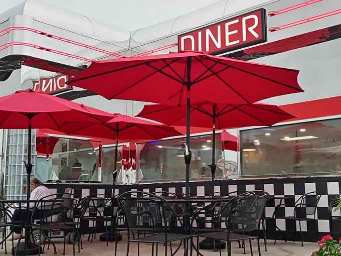 Bold red umbrellas, checkered patio walls, and open sky above. Outdoor dining with a serious sense of style.
