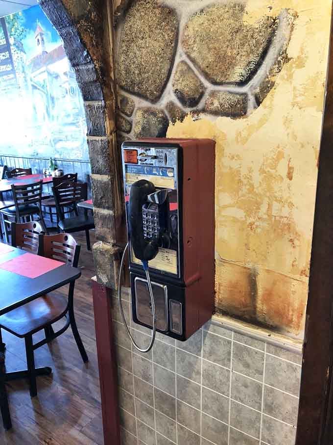 A working pay phone on a stone-textured wall. This charming relic says, "We've been here a while, and we're staying."
