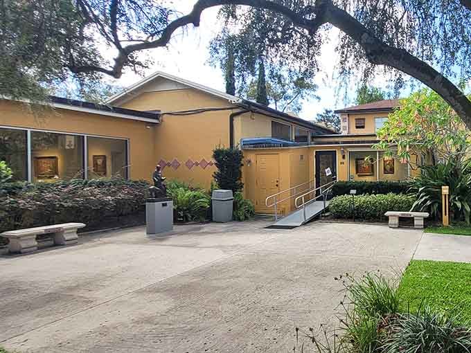 The warm yellow gallery building sits quietly among the trees, sculptures peeking out from the garden like they've always belonged there.