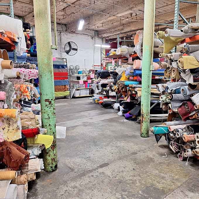 An aisle flanked by towering fabric rolls on both sides, the kind of view that makes crafters audibly gasp.
