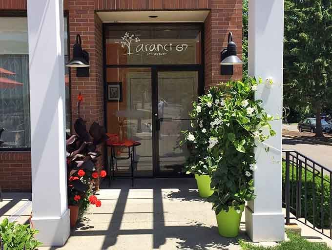 Flowering plants, black lantern sconces, and the Aranci 67 logo on the glass door, this entrance quietly says everything.