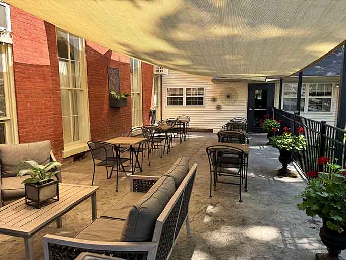 A shaded patio with comfortable seating, blooming red flowers, and brick walls. Outdoor dining doesn't get more inviting than this.