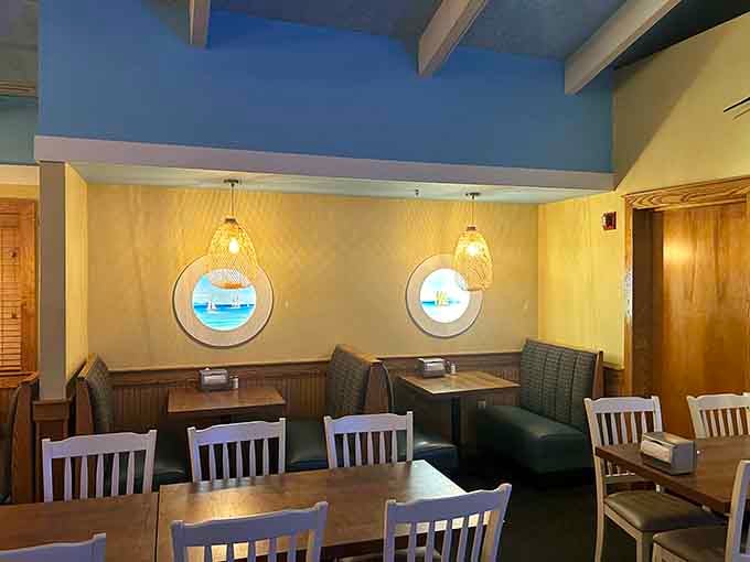 Round porthole windows with painted ocean scenes and cozy booth seating. Someone really committed to the nautical theme, and we're grateful.