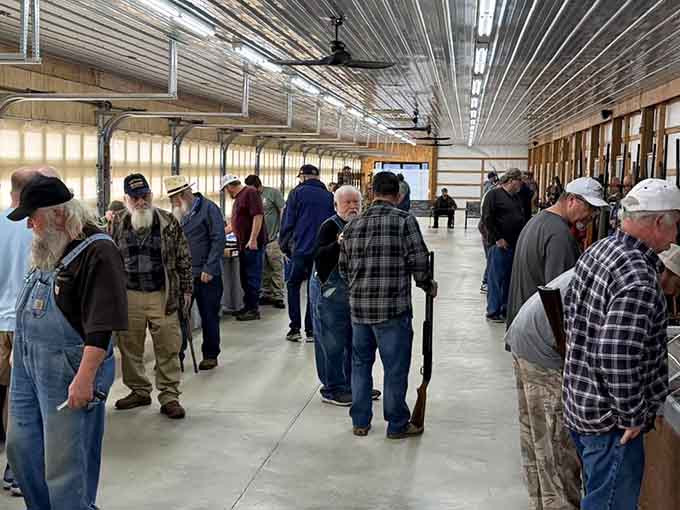 A room full of serious collectors examining antiques together, the kind of crowd that knows exactly what they're looking for and why it matters.