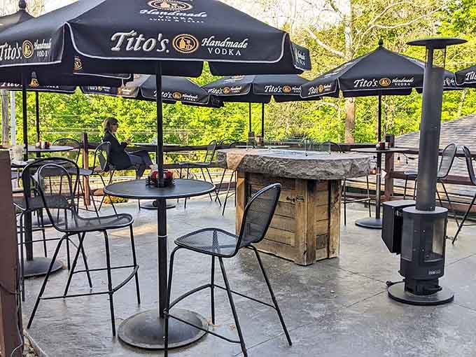 An outdoor patio surrounded by trees, with heaters ready for cooler evenings — nature and nachos, together at last.