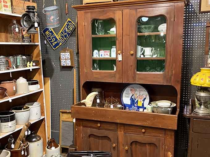 A pine hutch surrounded by crocks and license plates, rustic charm stacked floor to ceiling.