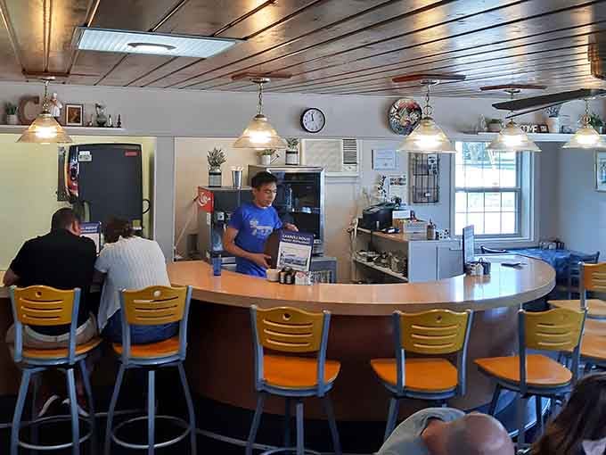 Counter seating with yellow chairs offers front-row views of the culinary magic happening just beyond the pass.