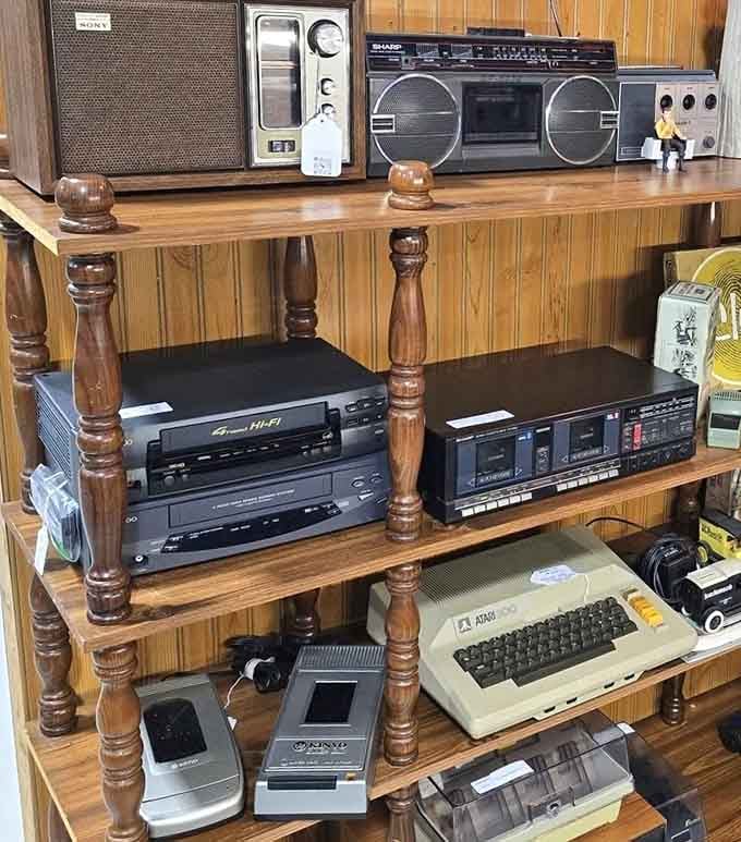 A Sony radio, Sharp boombox, VCR, and Atari 800 sharing a shelf like old friends reuniting.