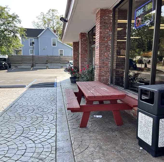 A red picnic table outside Dom Bakeries, because some donuts deserve fresh air and a little sunshine.