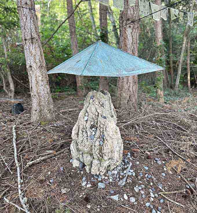 Sheltered beneath a weathered metal cap and surrounded by prayer flags, this textured stone shrine feels like a quiet conversation between earth and sky.