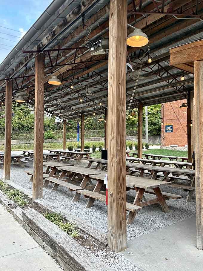 Rows of sturdy wooden picnic tables under a covered open-air pavilion, this patio was built for long afternoons and good company.