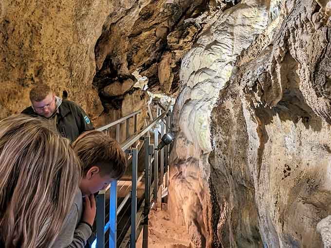 A ranger leads the way while a young visitor leans in close, already hooked on the story the cave is telling.