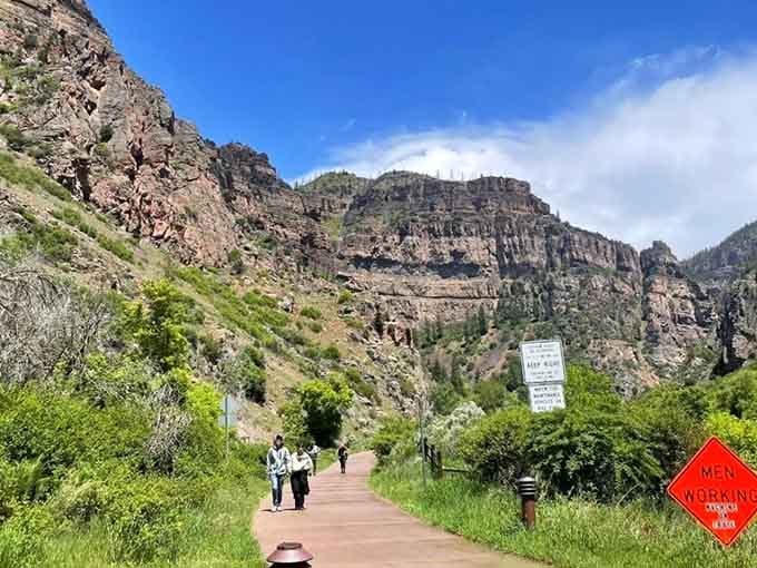 The paved approach welcomes hikers beneath dramatic cliffs, where millions of years of geology tower overhead impressively.