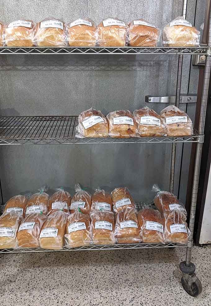 Rows of fresh white bread and raisin loaves on a rolling cart, golden and soft, like something straight out of your grandmother's kitchen.