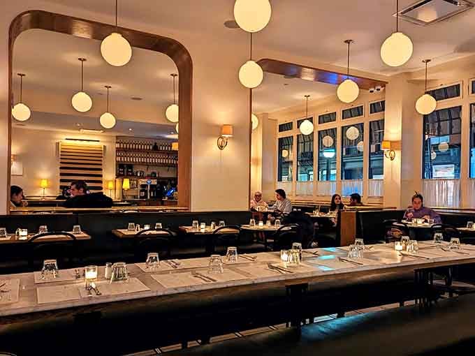 Globe pendant lights, soft cream walls, and a full dining room humming with energy. Pure New York magic.