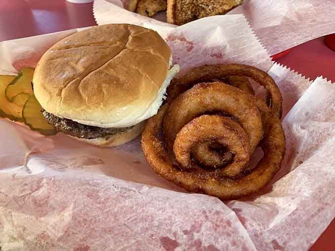 A classic burger beside a perfect spiral of onion rings: two legends sharing one very happy basket.