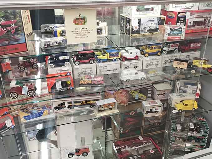 A glass case of die-cast collectible vehicles, tiny and perfect, each one a miniature trip down memory lane.
