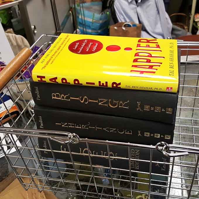 A shopping basket full of books, including a title called "Happier," which feels like the store is sending you a personal message.