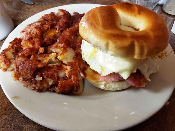 A ham, egg, and cheese sandwich on a bagel with crispy hash. Handheld happiness, no assembly required.