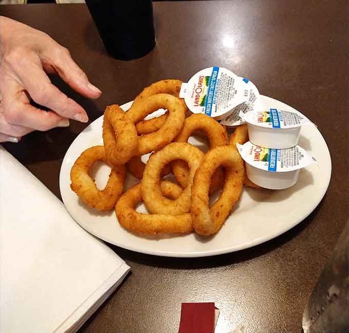 A plate of golden onion rings so perfectly stacked they deserve their own architectural award and immediate consumption.