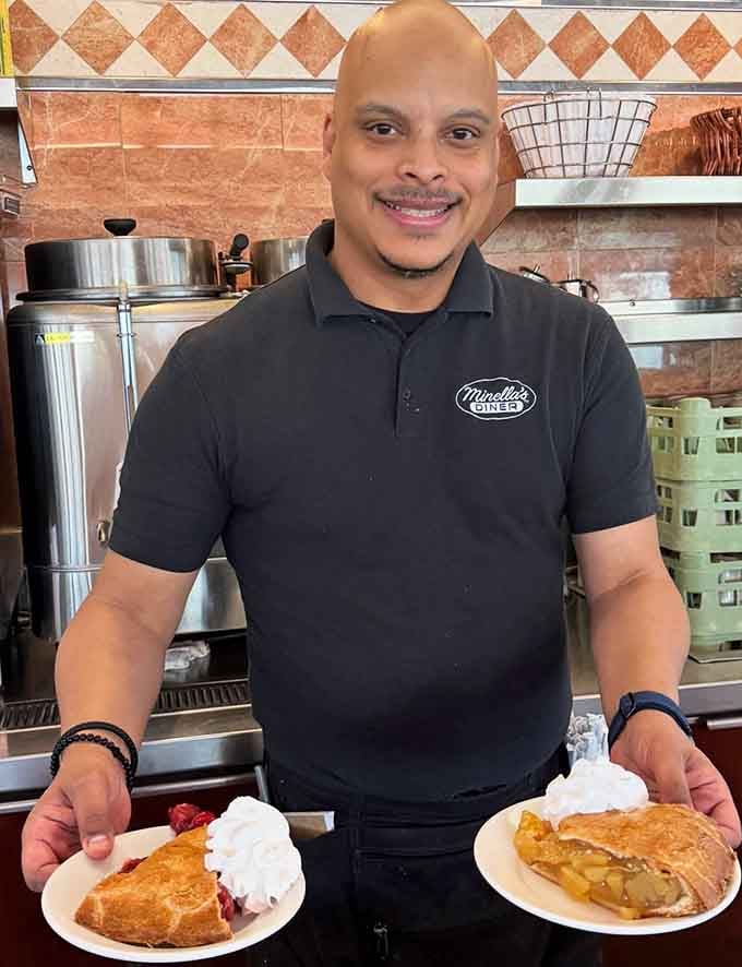 Two plates of pie with whipped cream and a smile that says he already knows you're going to love it.