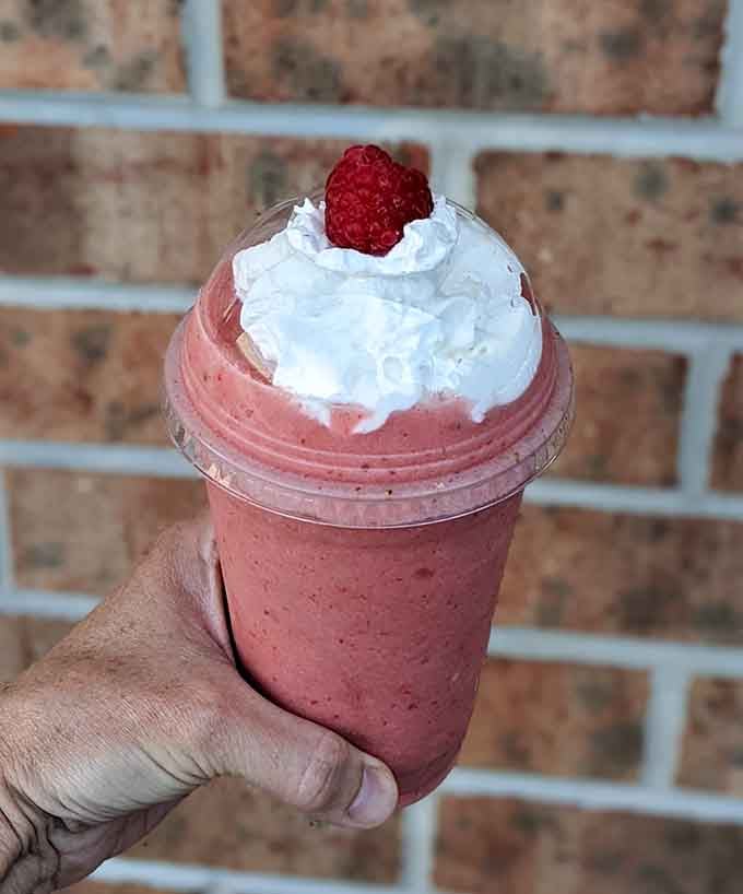 A raspberry milkshake topped with whipped cream and a fresh berry. Dessert just got serious.