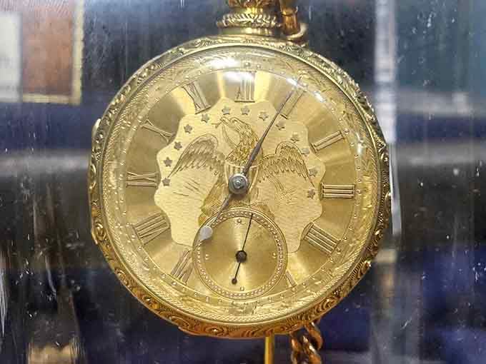 A gold pocket watch behind glass, carrying more history in its gears than most museums hold entirely.