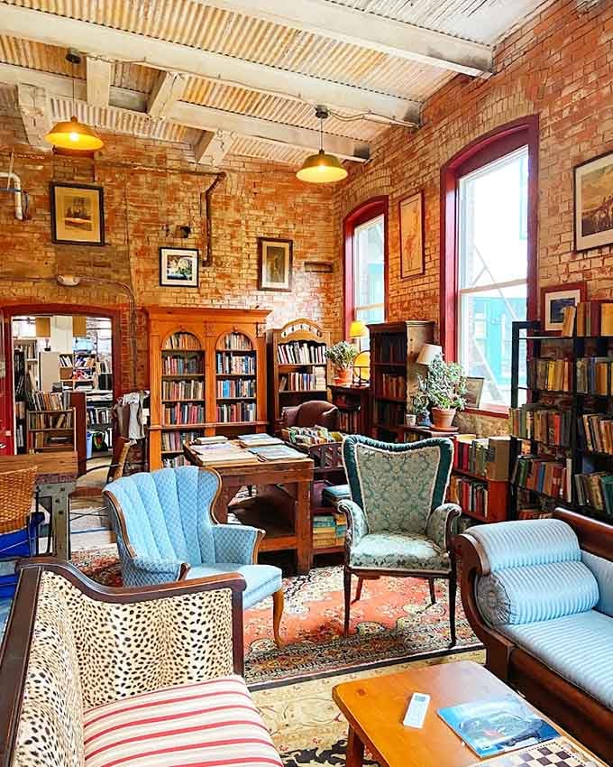 Warm pendant lights, rich brick walls, and mismatched wingback chairs that somehow look like they've always belonged together in this gorgeous room.