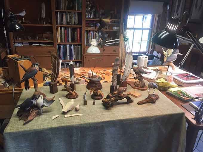 Delicately carved wooden birds perched across a craftsman's worktable, each one a tiny masterpiece that took patience, skill, and a very steady hand.