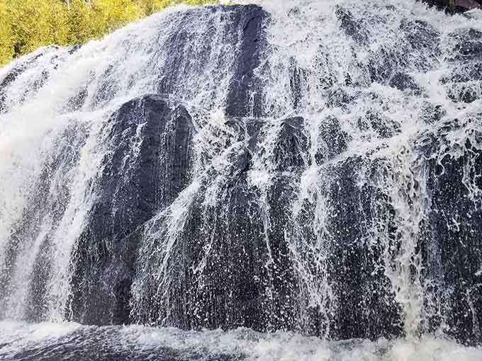 Up close, the water fans across dark rock in thin white ribbons that shimmer like something alive.