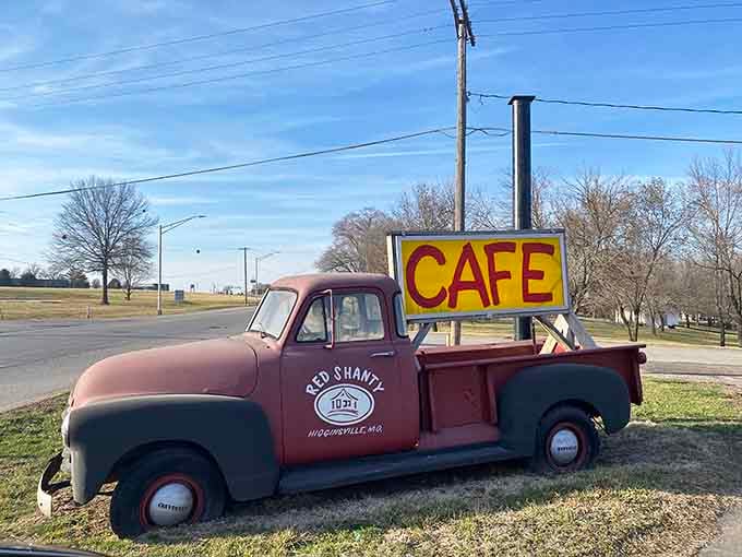 An old truck carrying a bright yellow cafe sign roadside, the kind of landmark that makes you hit the brakes immediately.