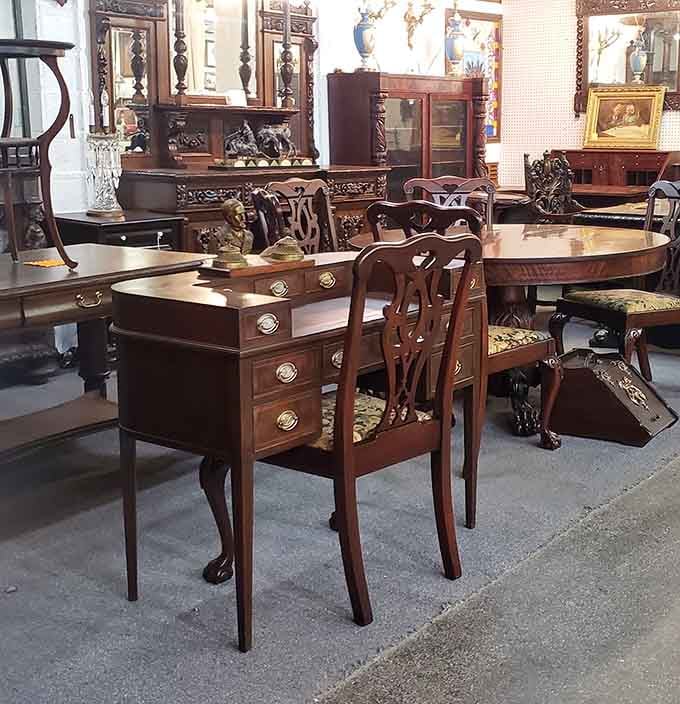 Richly carved antique furniture fills one section like a formal dining room that somehow wandered into a market.