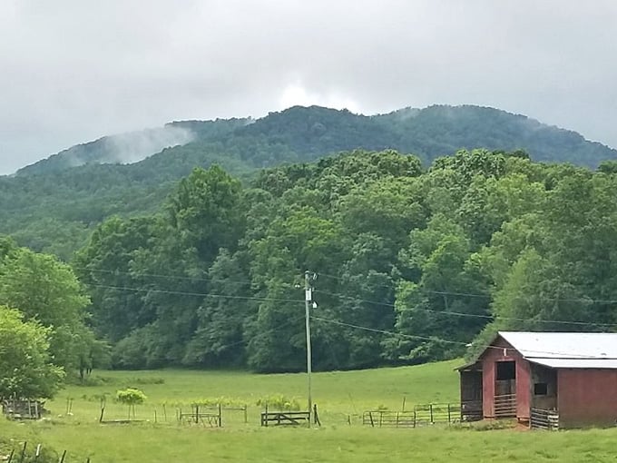 Red barn against green mountains, like someone painted the perfect postcard and left it here.