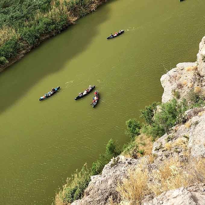 From up here, the kayakers look like colorful confetti floating through the most dramatic punch bowl ever made.