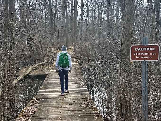The boardwalk stretches into the bare winter forest, and yes, that caution sign means business.