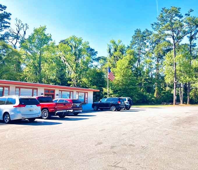 A sunny parking lot full of cars beneath tall Georgia pines. The crowd outside tells you everything you need to know.