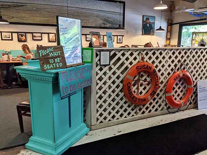 A turquoise hostess stand, a life ring, and a "Please Wait to Be Seated" sign that somehow feels genuinely welcoming.