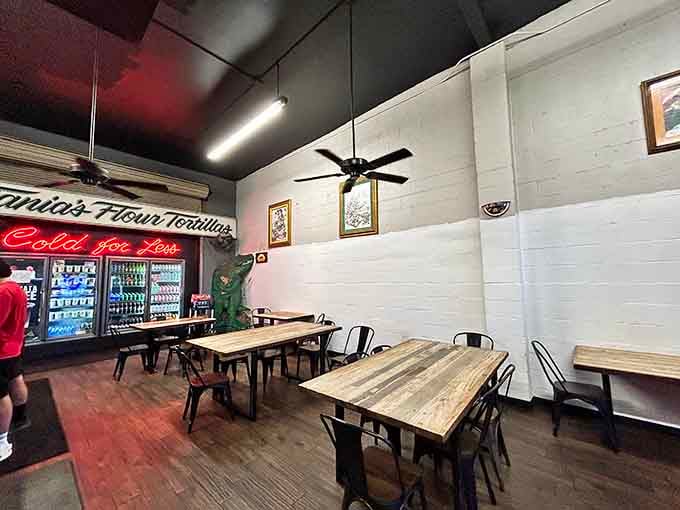 Framed artwork, wooden tables, and a neon "Cold for Less" sign. Comfort never looked so honest.