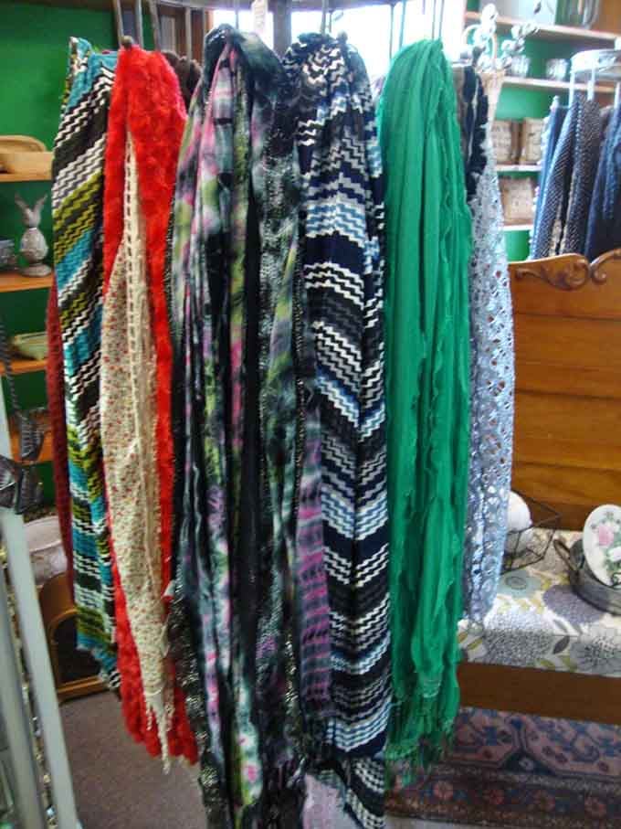 A rainbow of vintage scarves hanging in a row, bold, textured, and impossible to walk past without touching.
