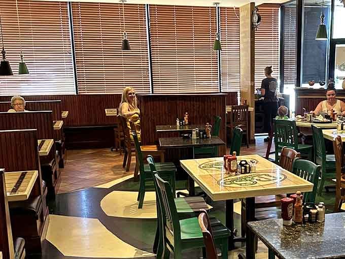 Green chairs, bold floor graphics, and warm wood paneling create a dining room that feels genuinely lived-in and loved.