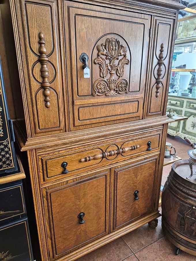 A beautifully carved wooden cabinet that looks like it belongs in a manor house, not a resale shop in Florida.