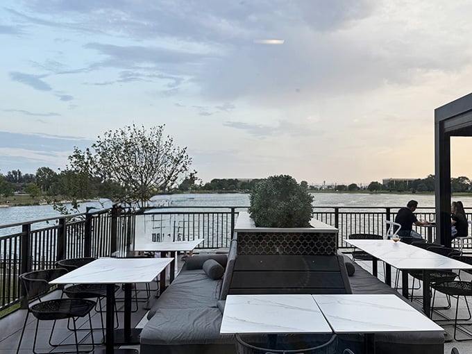 A lakeside patio at dusk, with marble-top tables and the kind of view that makes you forget your phone exists.