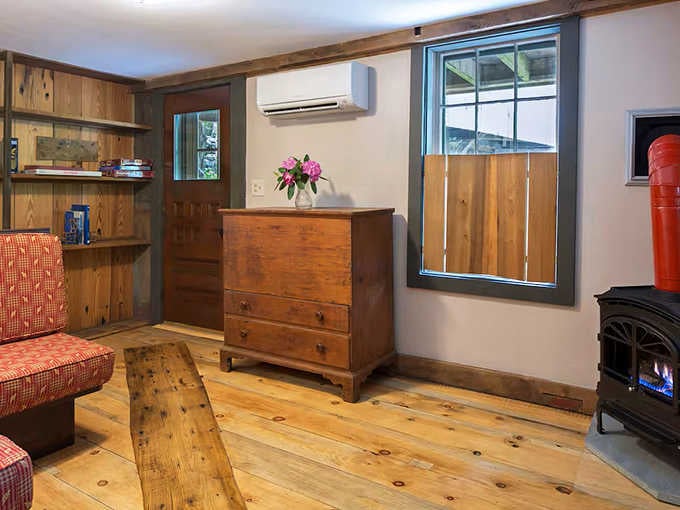 Wide plank floors, a glowing stove, and fresh flowers. Somebody here really understands how comfort works.