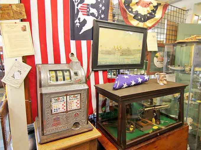 A vintage slot machine next to a folded flag and framed maritime art, American history in one very interesting corner.
