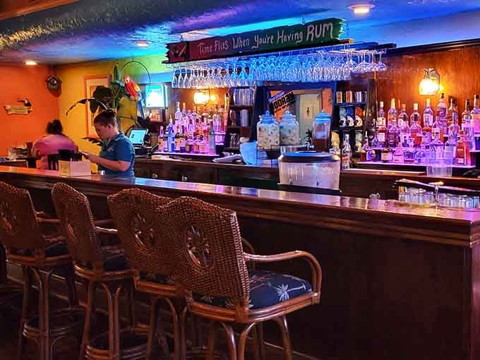 Wicker bar stools, a glowing back bar stacked with bottles, and a sign that already knows why you're here.