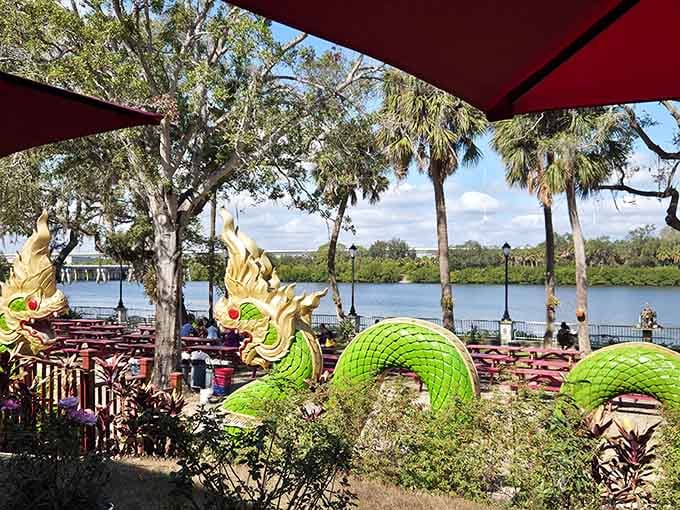 Relax at outdoor picnic tables by the scenic waterfront, guarded by beautiful, vibrant green and gold dragon statues.