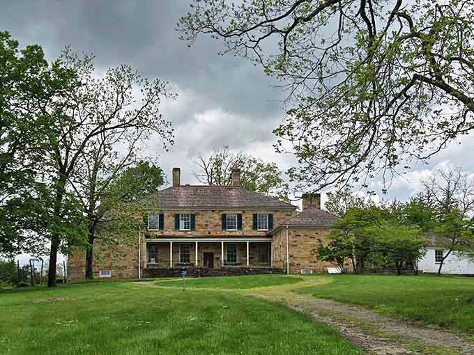 Dramatic storm clouds rolling over Adena's stone facade and front portico give this historic mansion a genuinely cinematic presence.