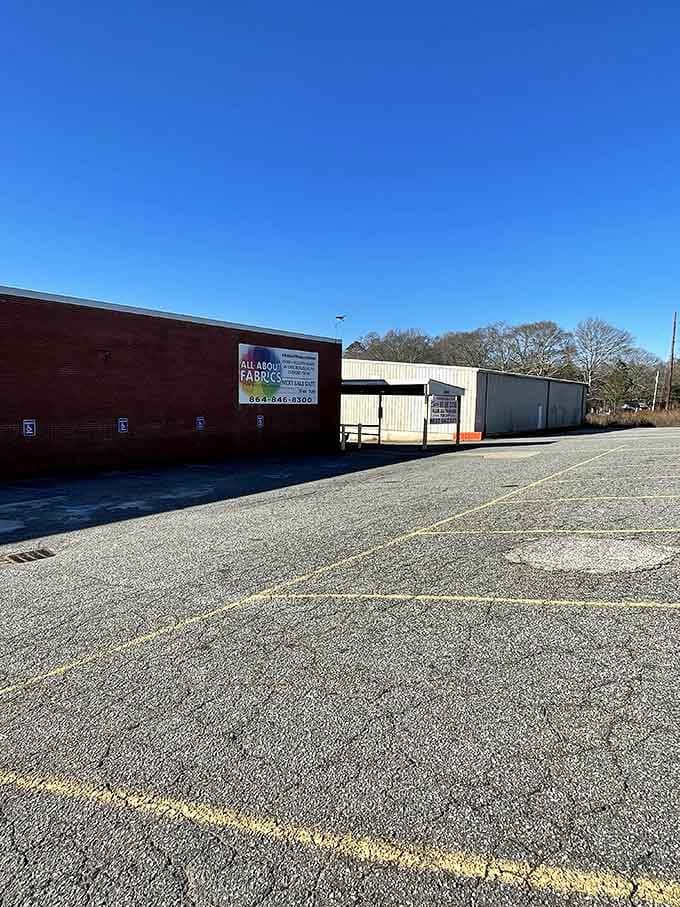 A wide open parking lot greets you at All About Fabrics, the calm before a very colorful, very wonderful storm.